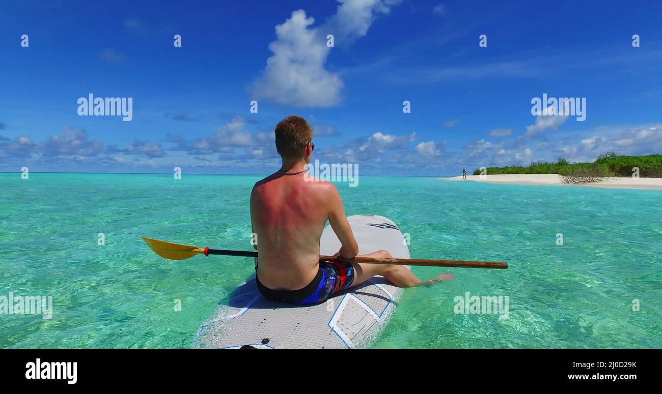 Back view of a male with a sunburn on a paddleboard near Rasdhoo Island ...