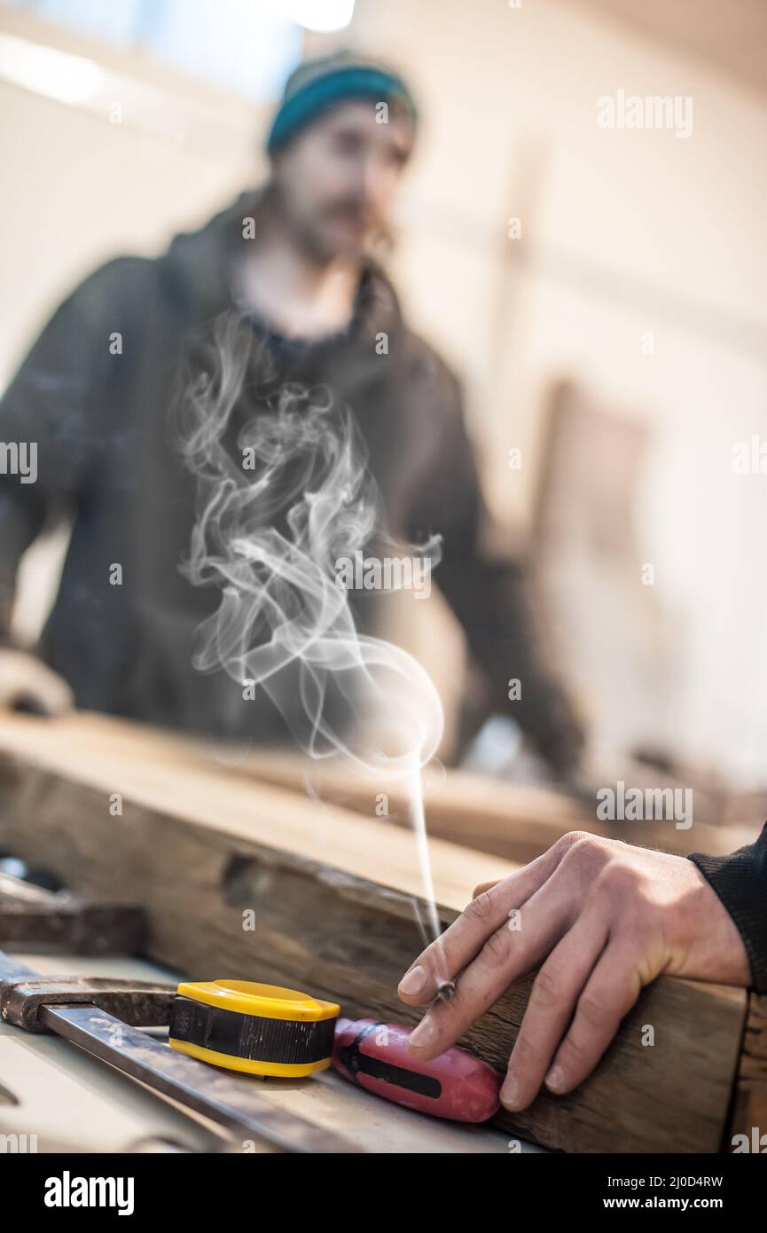 Carpenter smoking cigarette in workshop Stock Photo - Alamy