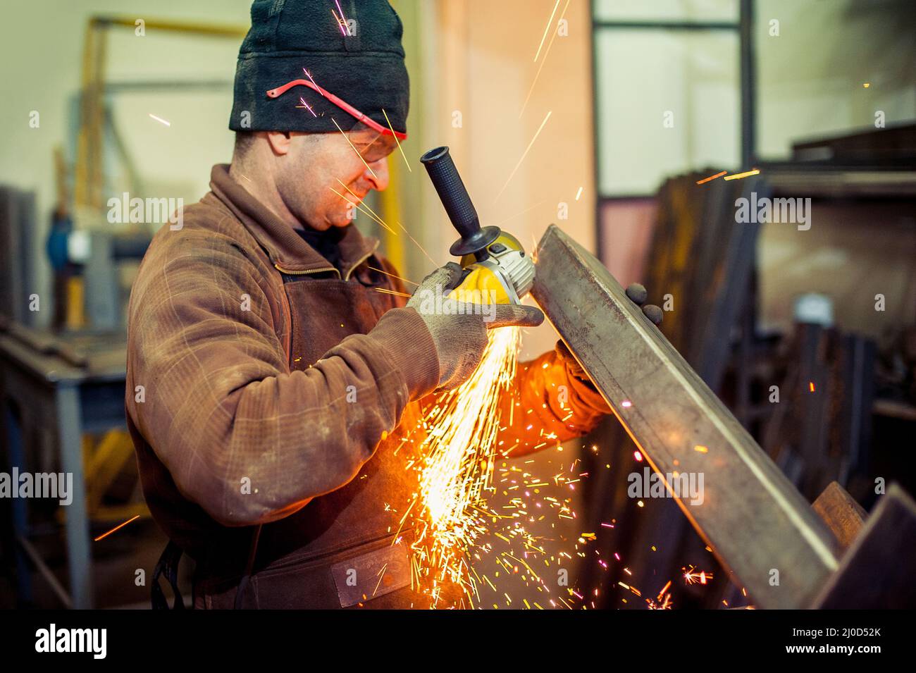 A man working with electric grinder tool on steel structure in factory ...