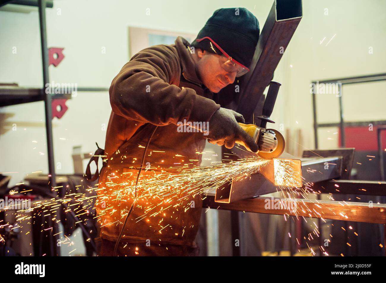 A man working with electric grinder tool on steel structure in factory ...