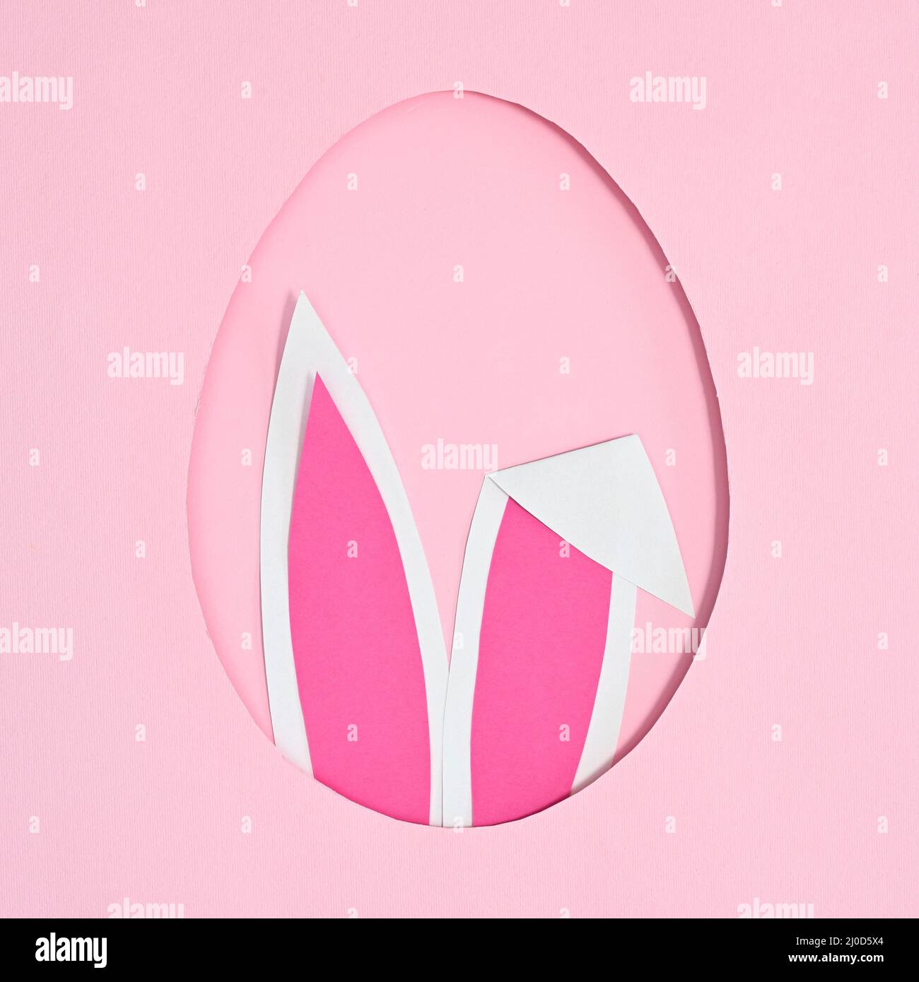 Egg shape frame with rabbit ears peek from hole on pastel pink ...