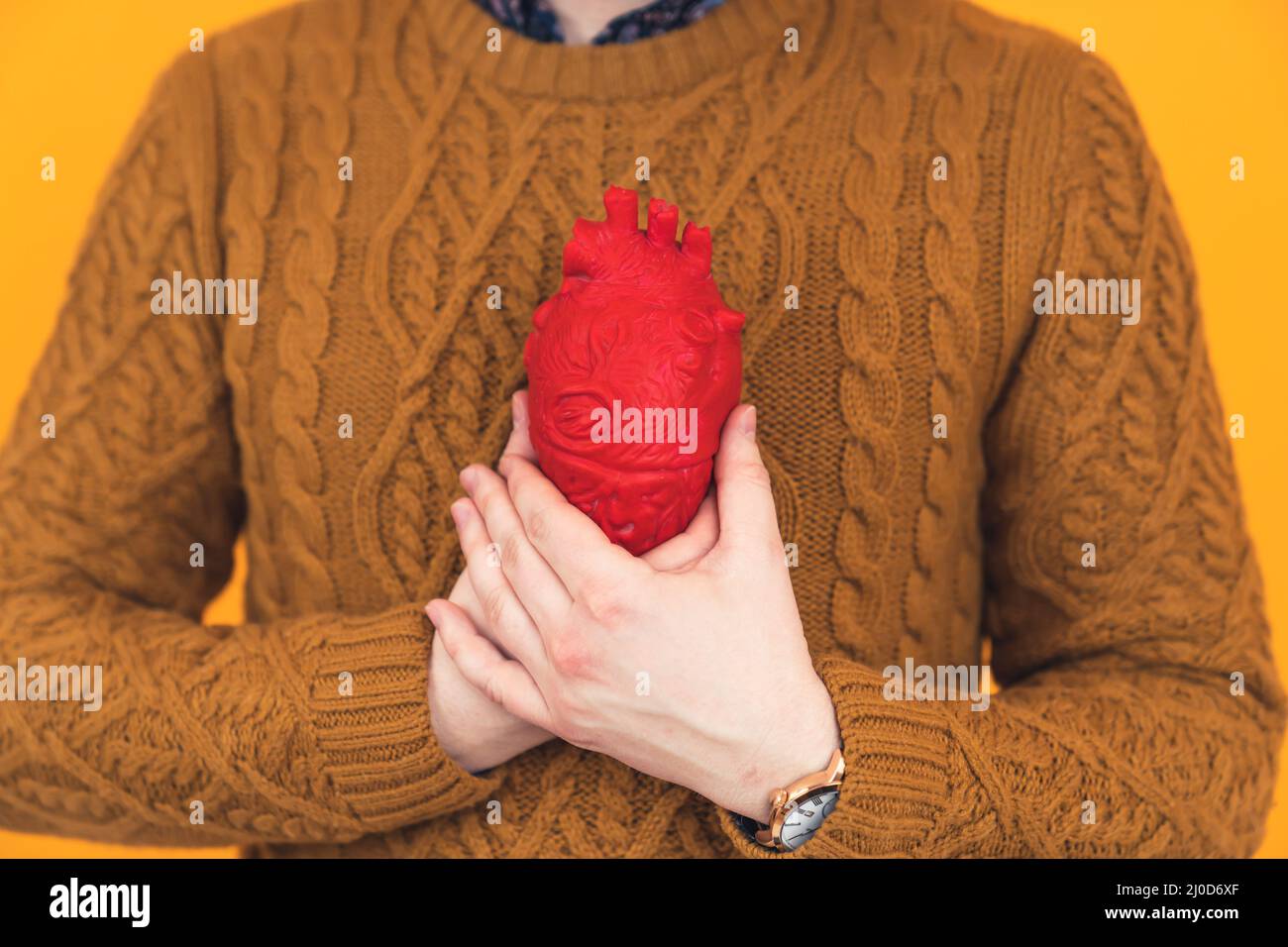 caucasian man holding a plastic heart close to his body without his ...
