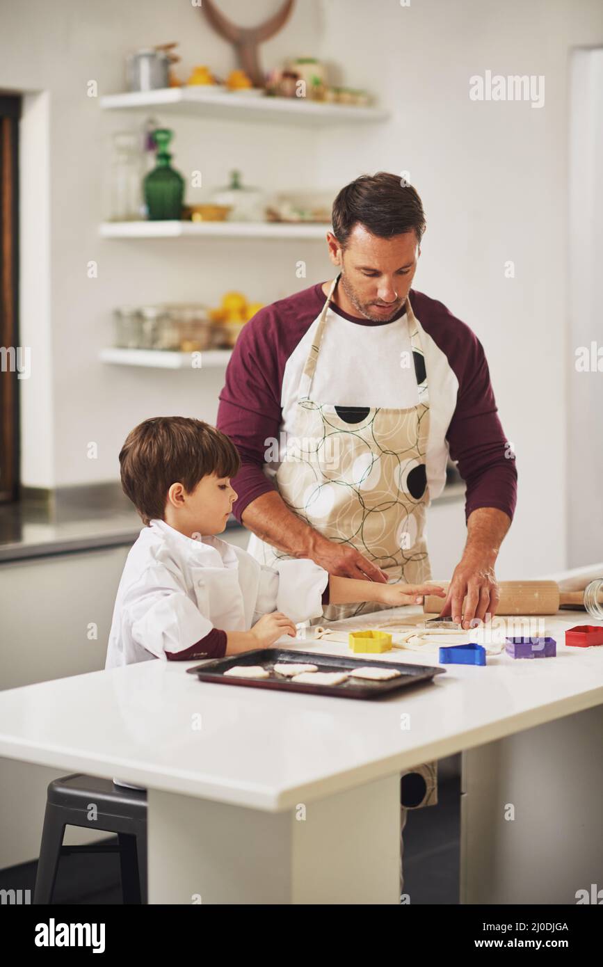 Baking and bonding. Shot of a father and his young son baking cookies ...
