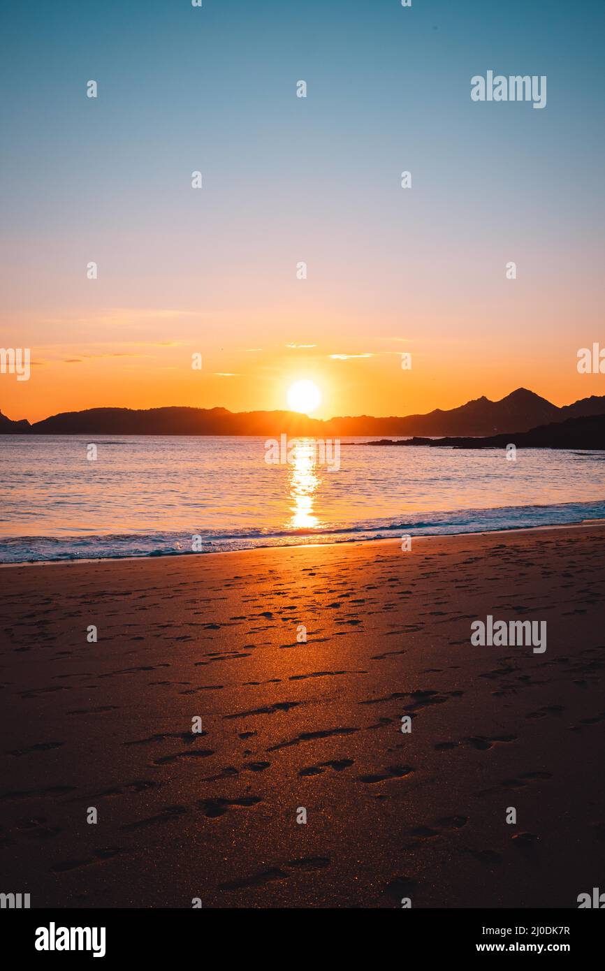 Vertical sunset shot over a sandy beach surrounded by mountains Stock ...