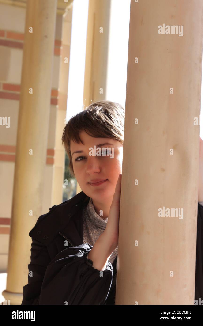 Portrait of a girl behind a column Stock Photo - Alamy
