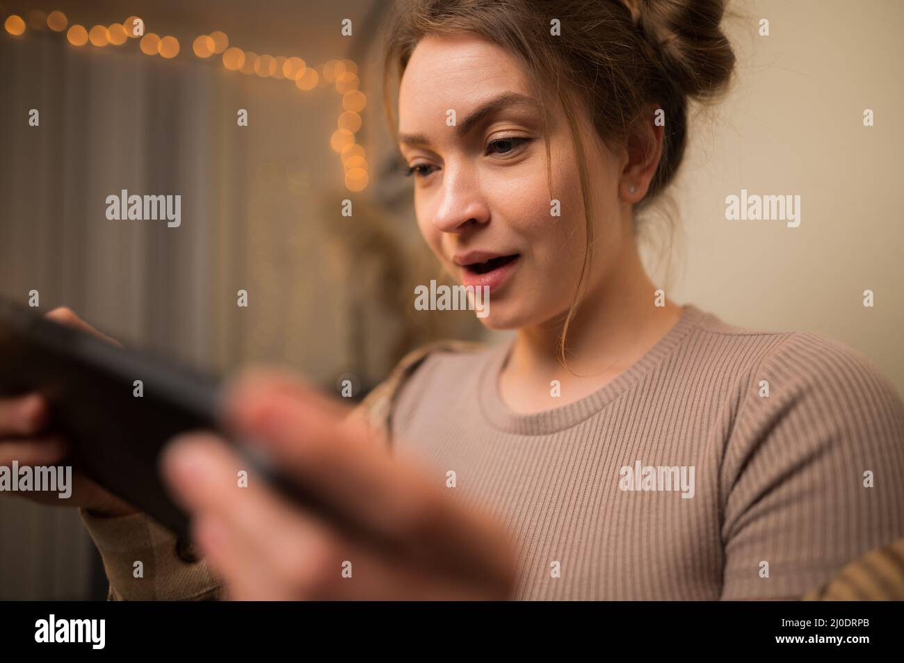Blond young woman reads a text message on a smartphone. There is ...