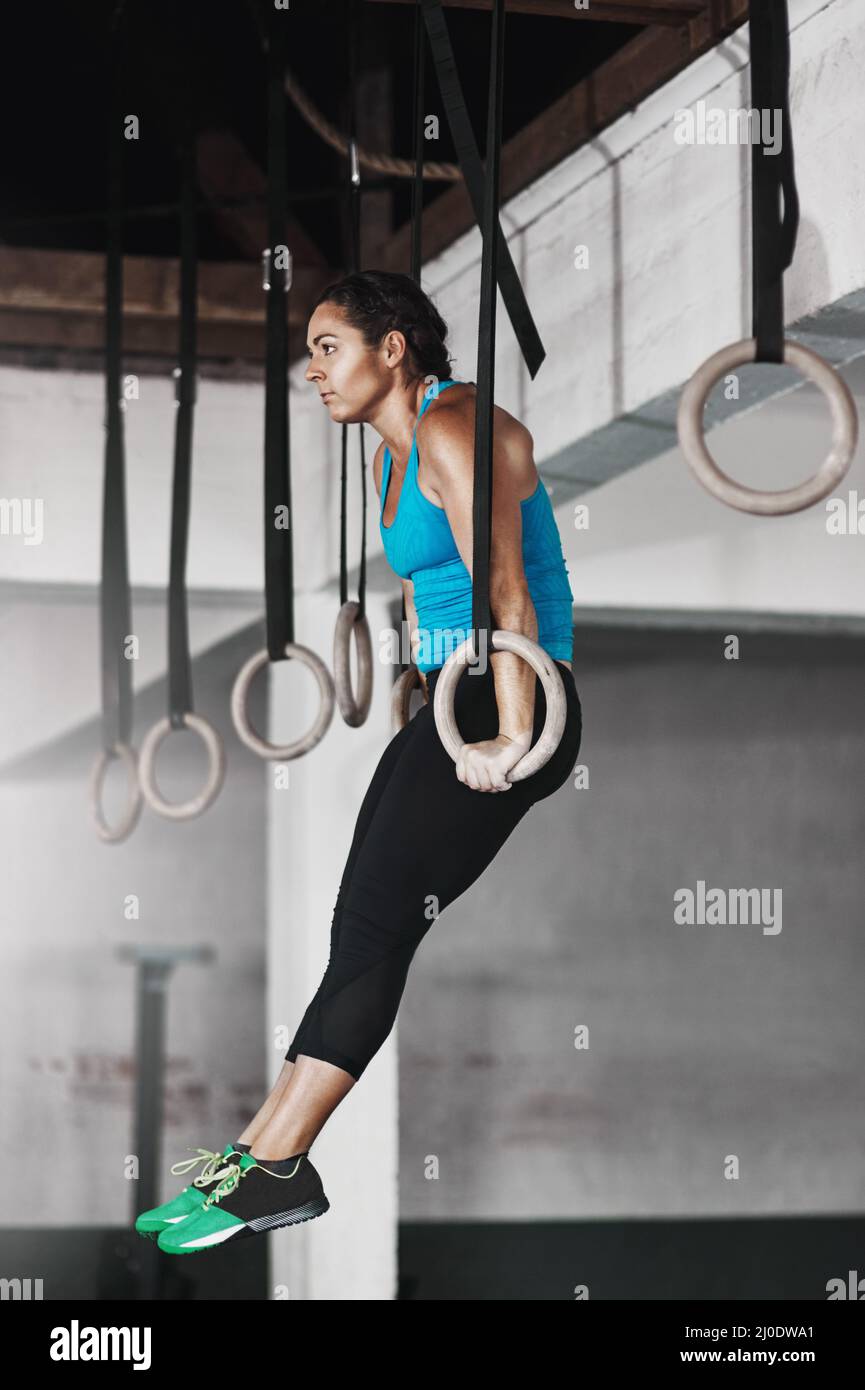 On the rings. Full length shot of a young woman working out on the ...