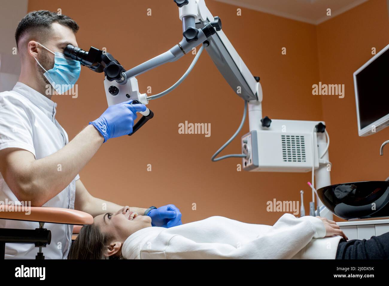 Dentist looking through a microscope at the patient's teeth. Modern ...