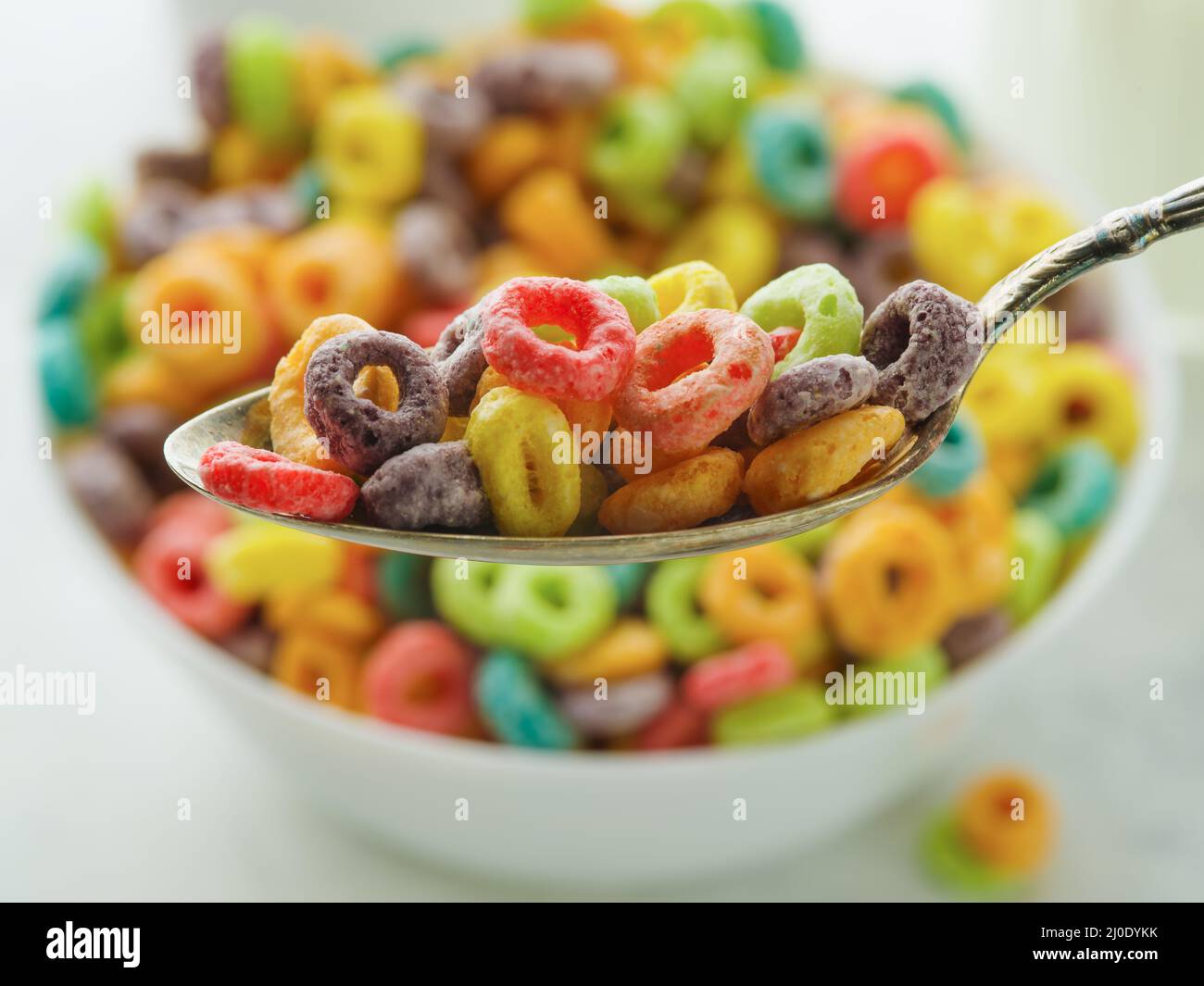 Macro shot. Crispy cereal rings in different colors on a spoon and in a ...