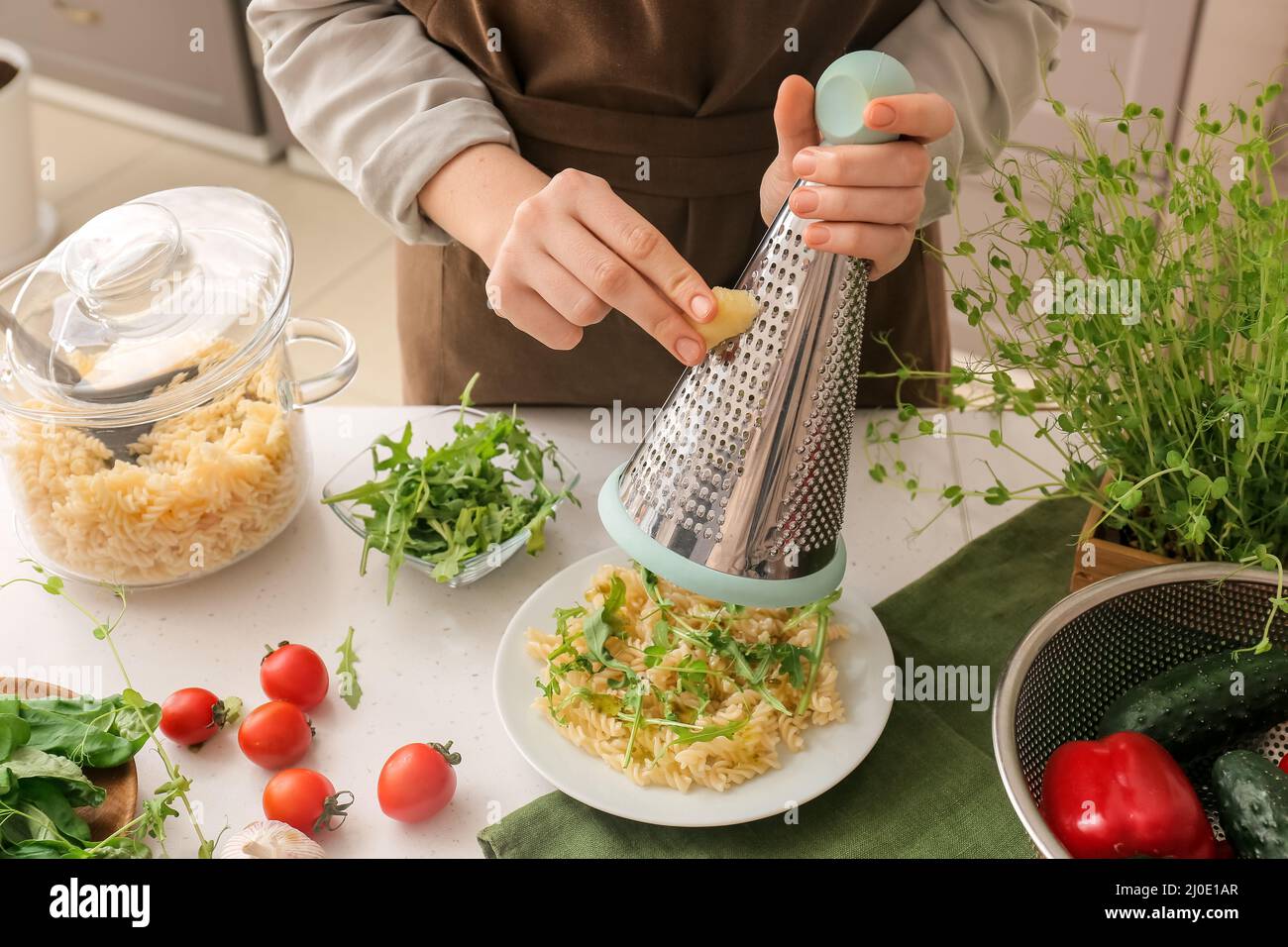 Woman grating cheese onto pasta in kitchen Stock Photo - Alamy