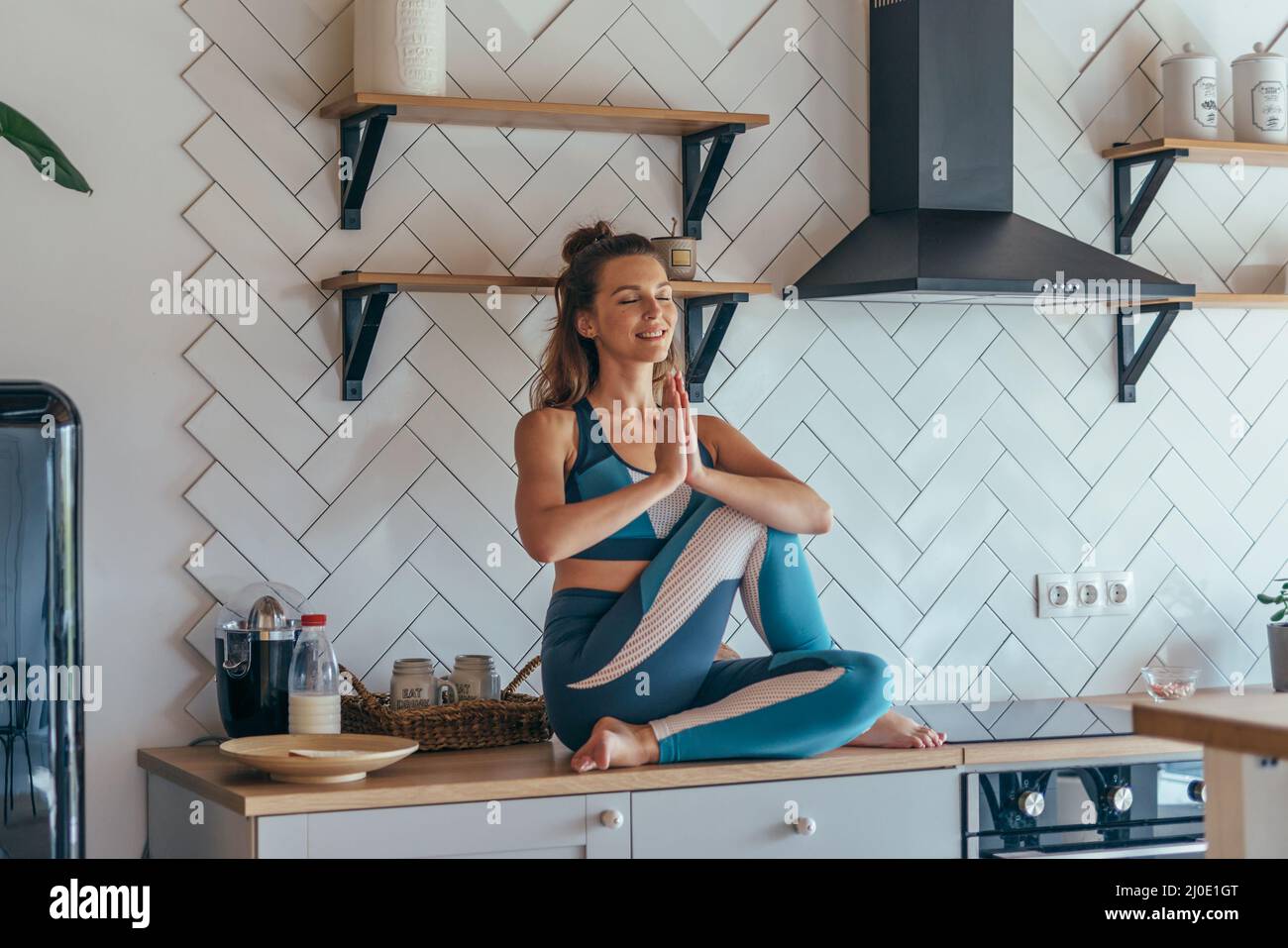 Girl in the kitchen meditating practicing yoga Stock Photo - Alamy