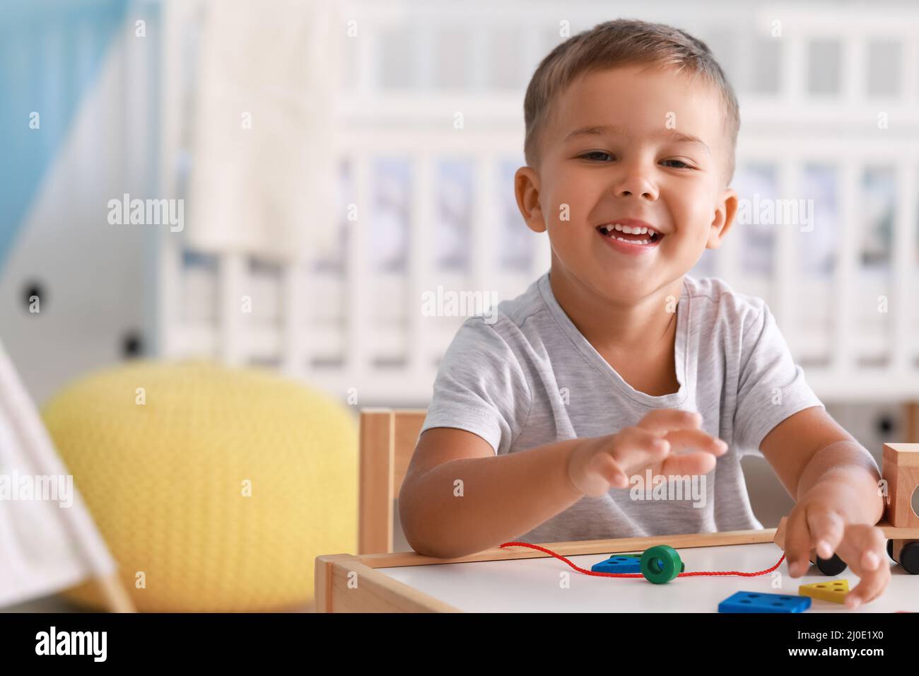 Cute little boy playing with wooden toys at table in room Stock Photo ...