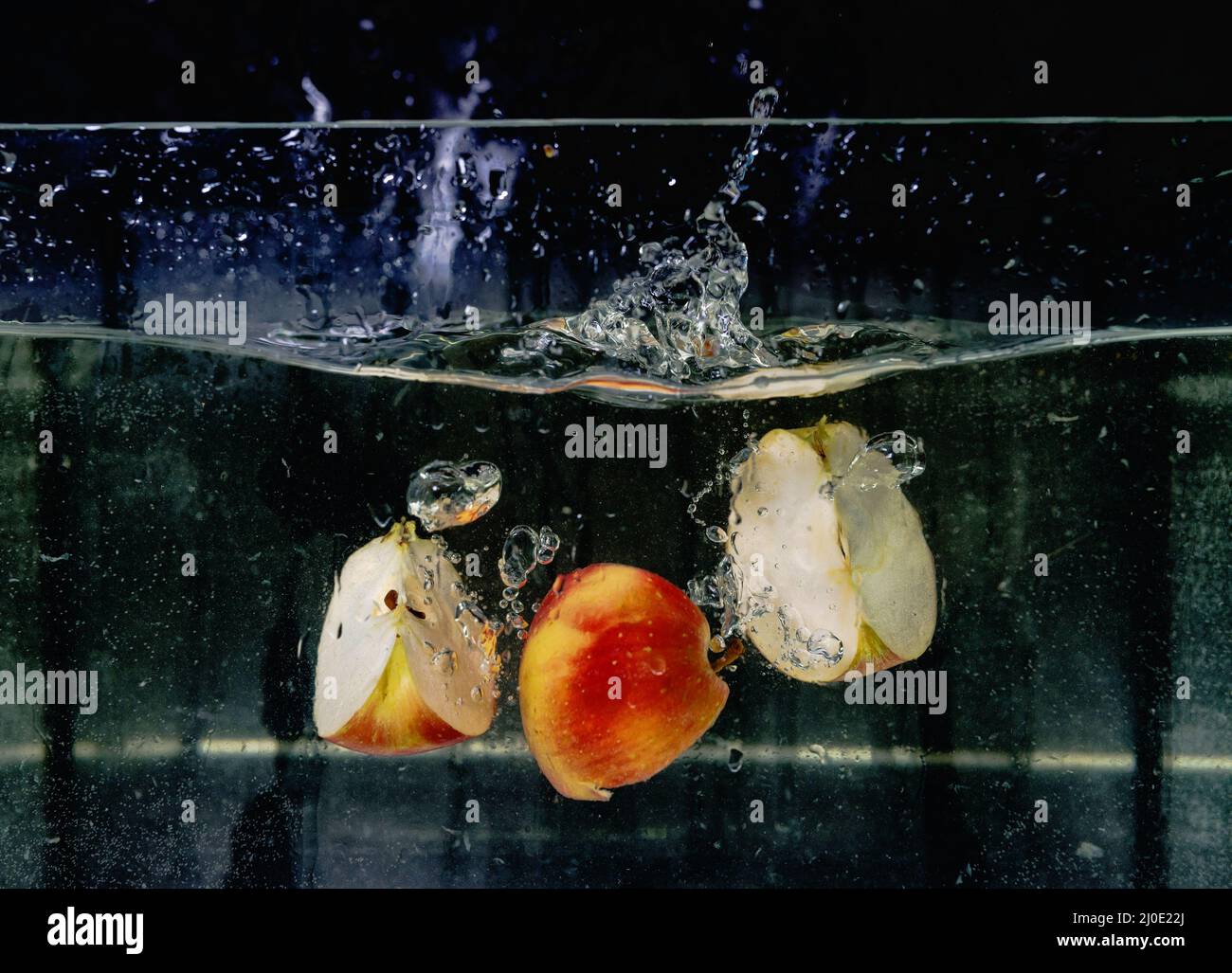 sliced apples falling in the water on dark background. Underwater view ...
