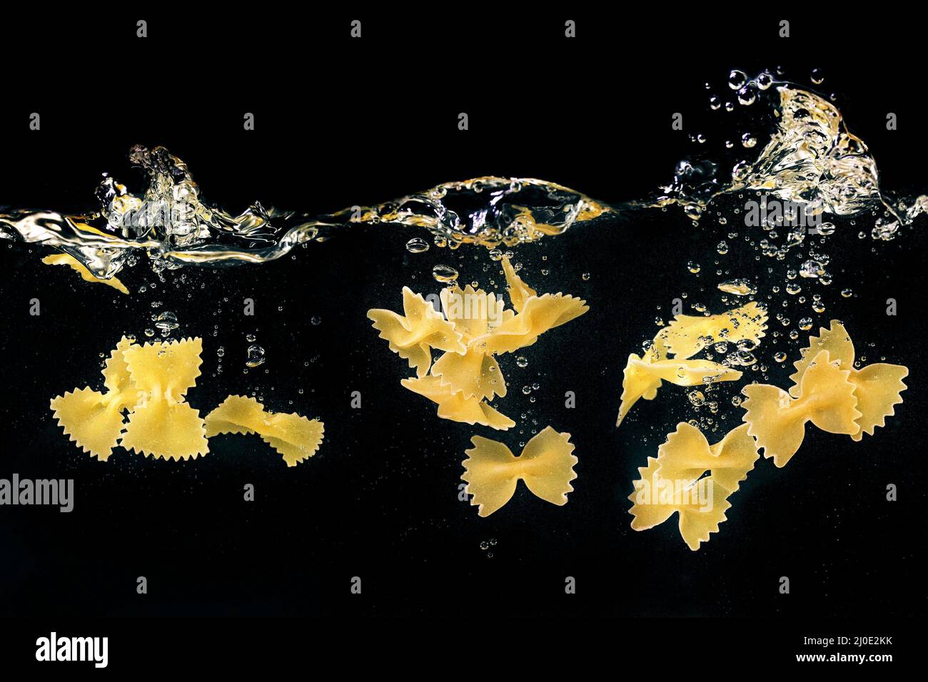 butterflies pasta falling in the boiling water on dark background ...