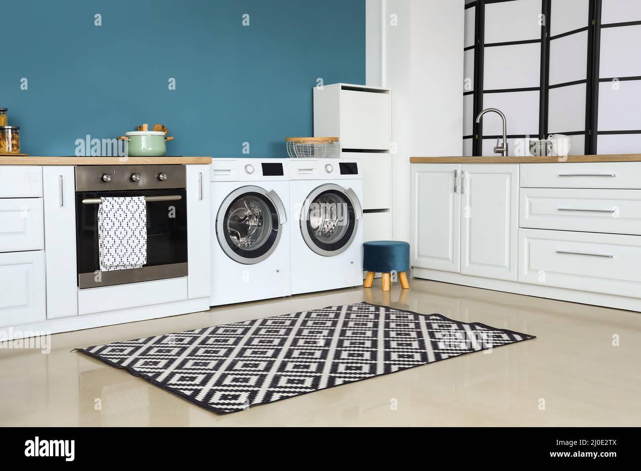 Interior of stylish kitchen with modern washing machines, oven and ...