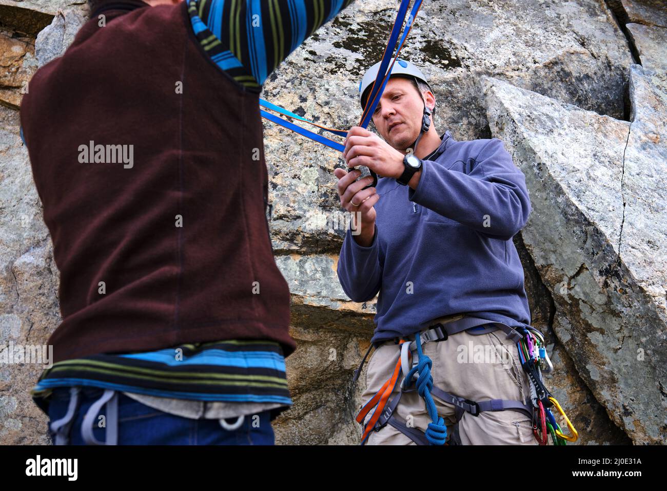 Rock climbing instructor is teaching how to perform the belay station ...