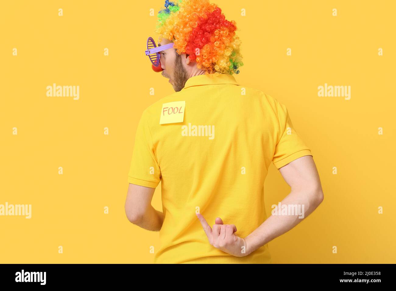 Funny man in disguise and with sticky note on his back against yellow ...