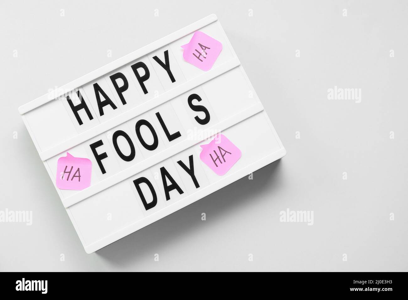 Board with text HAPPY FOOLS DAY and sticky notes on light background ...