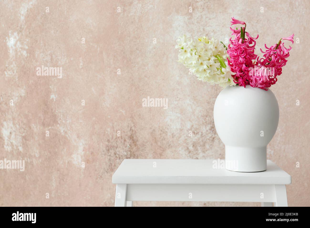 Vase with hyacinth flowers on stepladder stool near color wall Stock ...