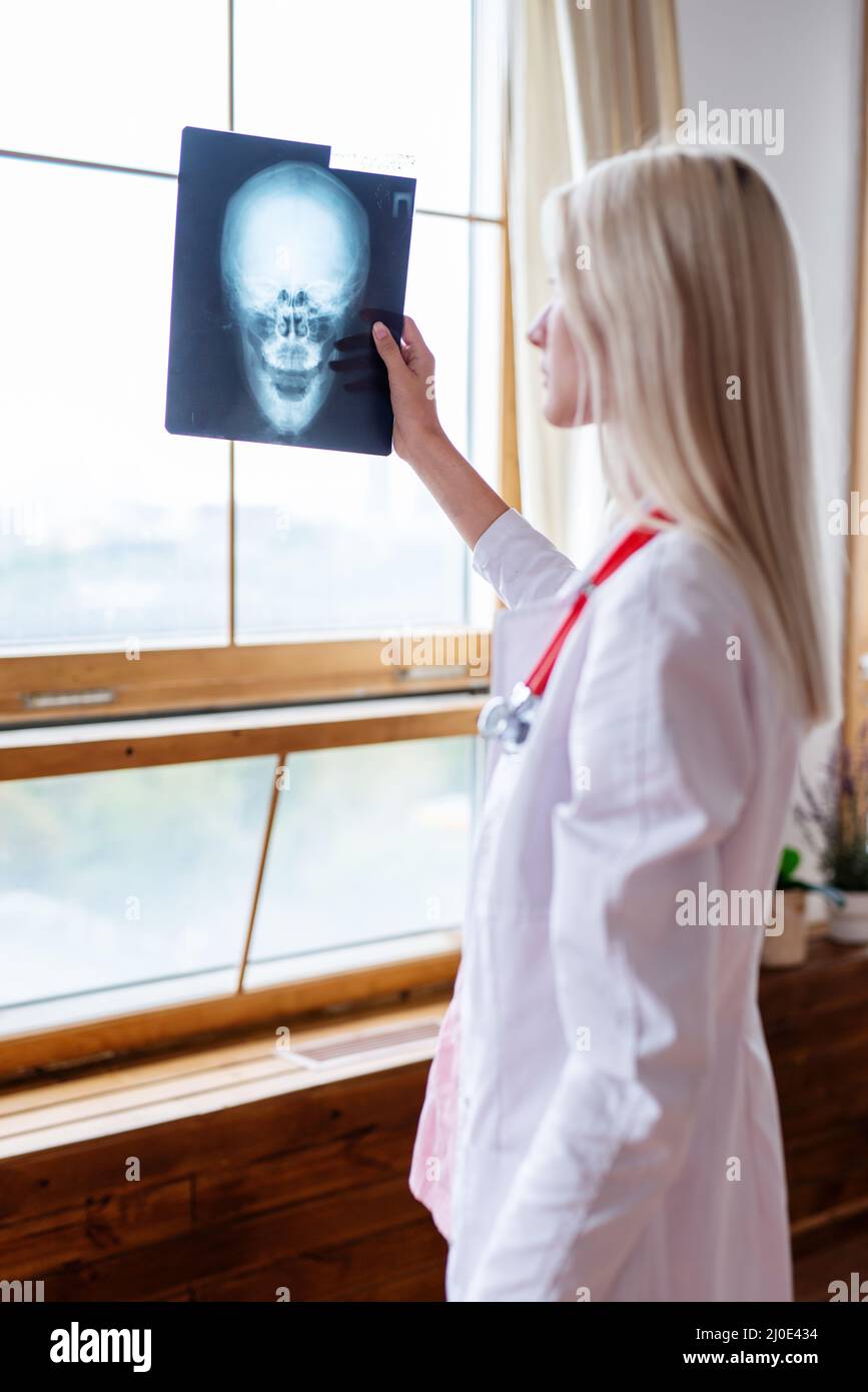 Woman doctor at window looking at skull scan Stock Photo - Alamy