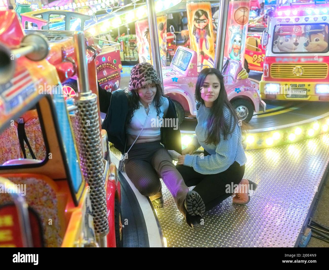 Tow view of two friends sitting on the platform of an attraction in a ...