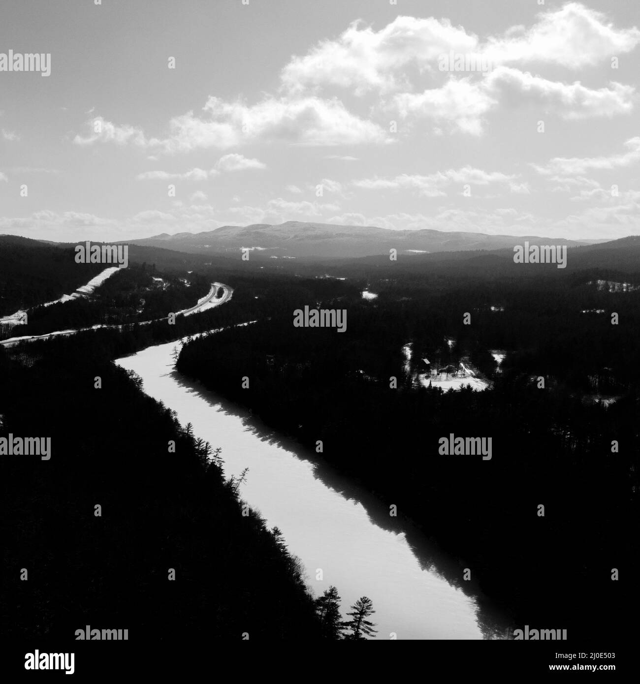 Grayscale of a landscape with a river in a forest under the clear sky ...