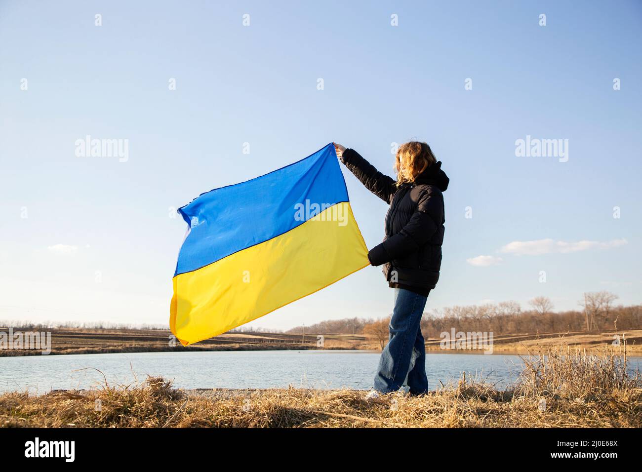 Ukrainian yellow-blue flag against the sky in the hands of a young ...