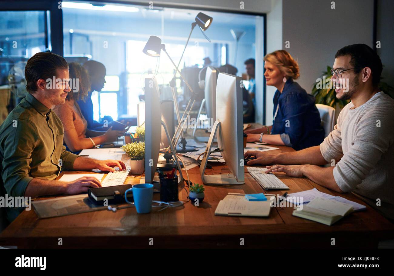 Happily working those long hours. Shot of a team of young ...