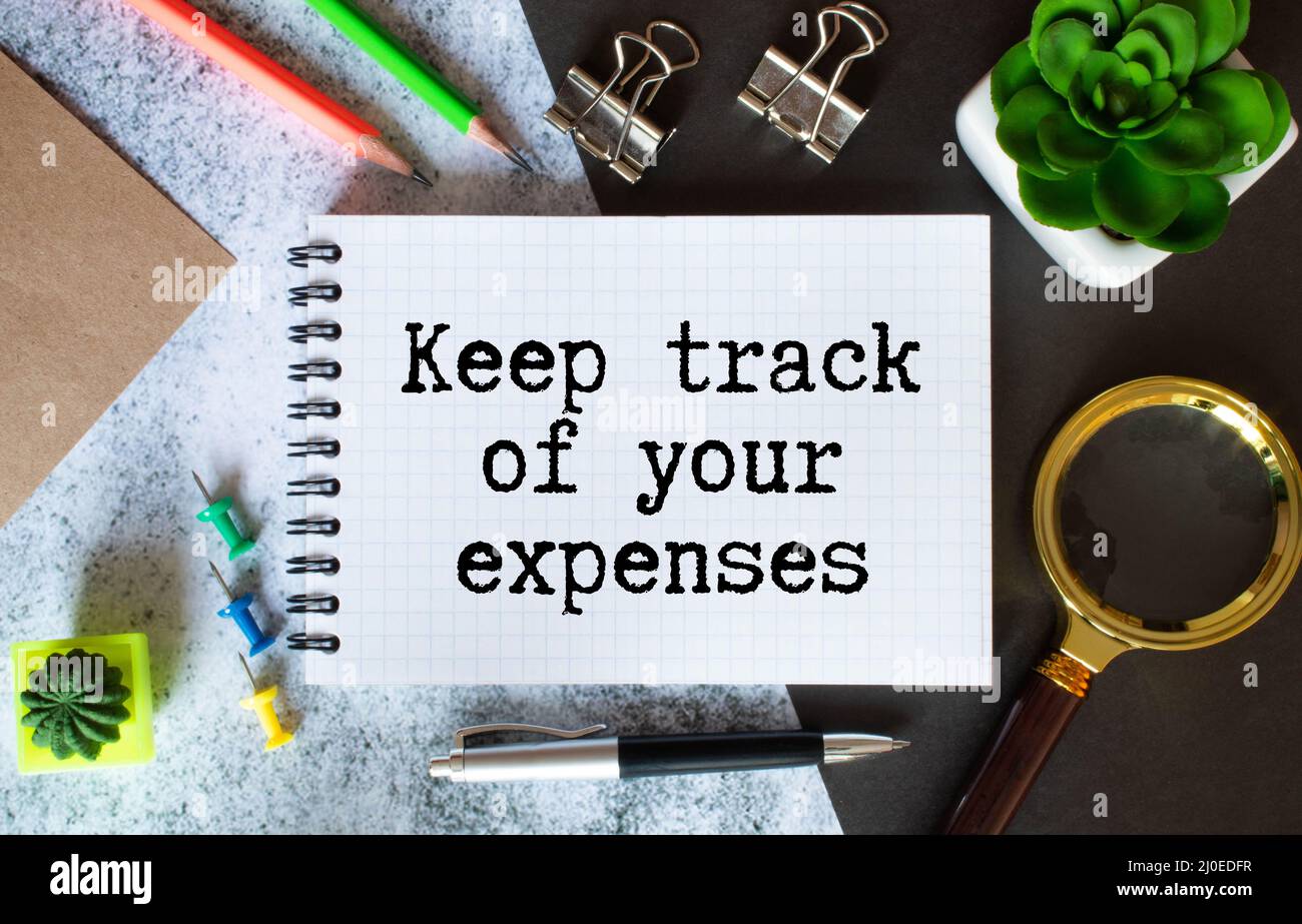White card with the text Keep track of your expenses on wooden desk ...