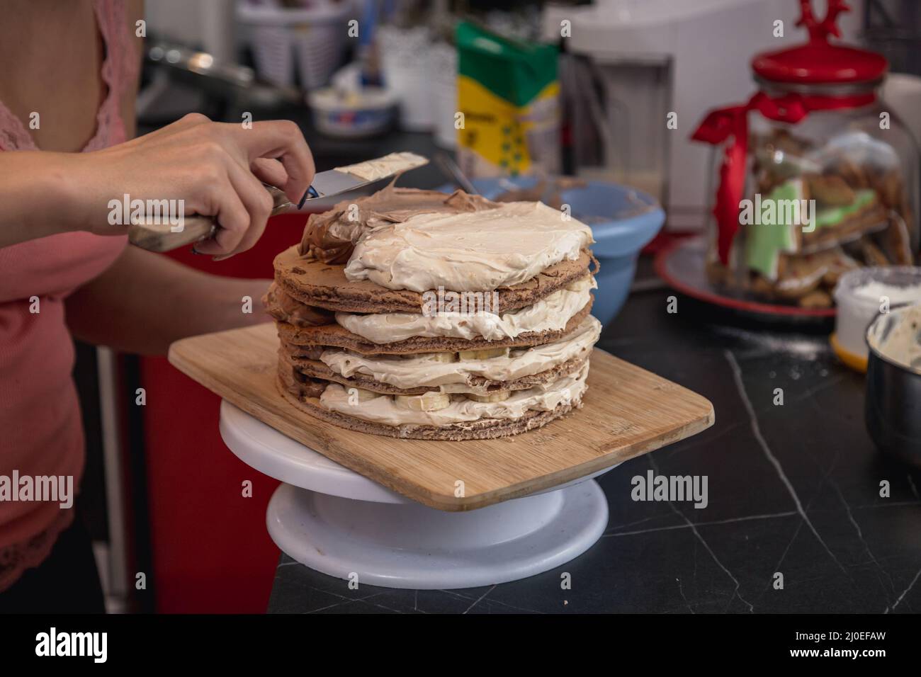 Female preparing a multi-layered cake with cream Stock Photo - Alamy