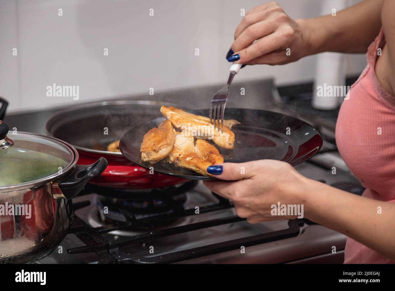 Female frying chicken and putting on a plate Stock Photo - Alamy
