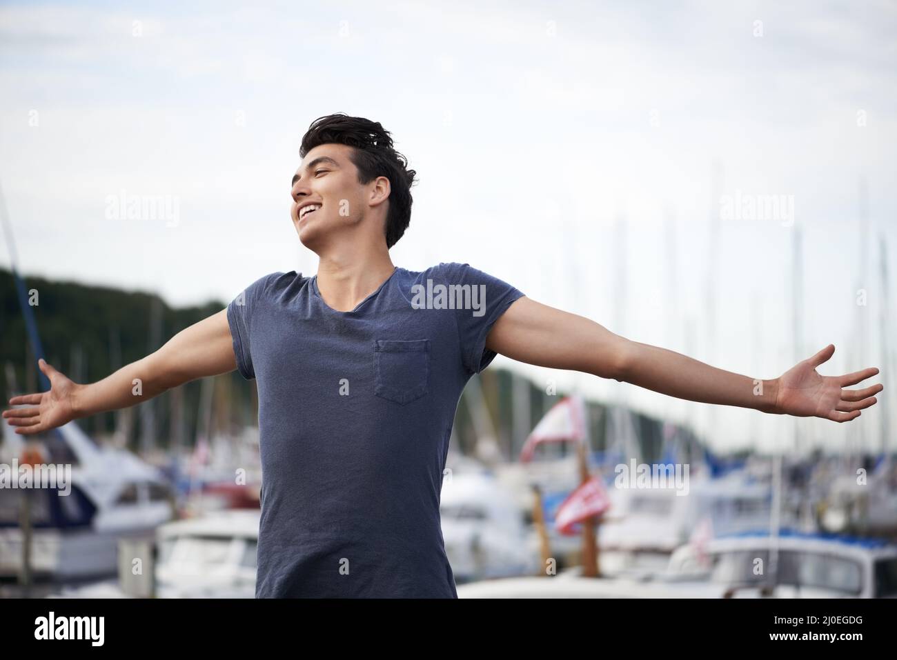 Feeling free and alive. A young man with arms outstretched relishing ...