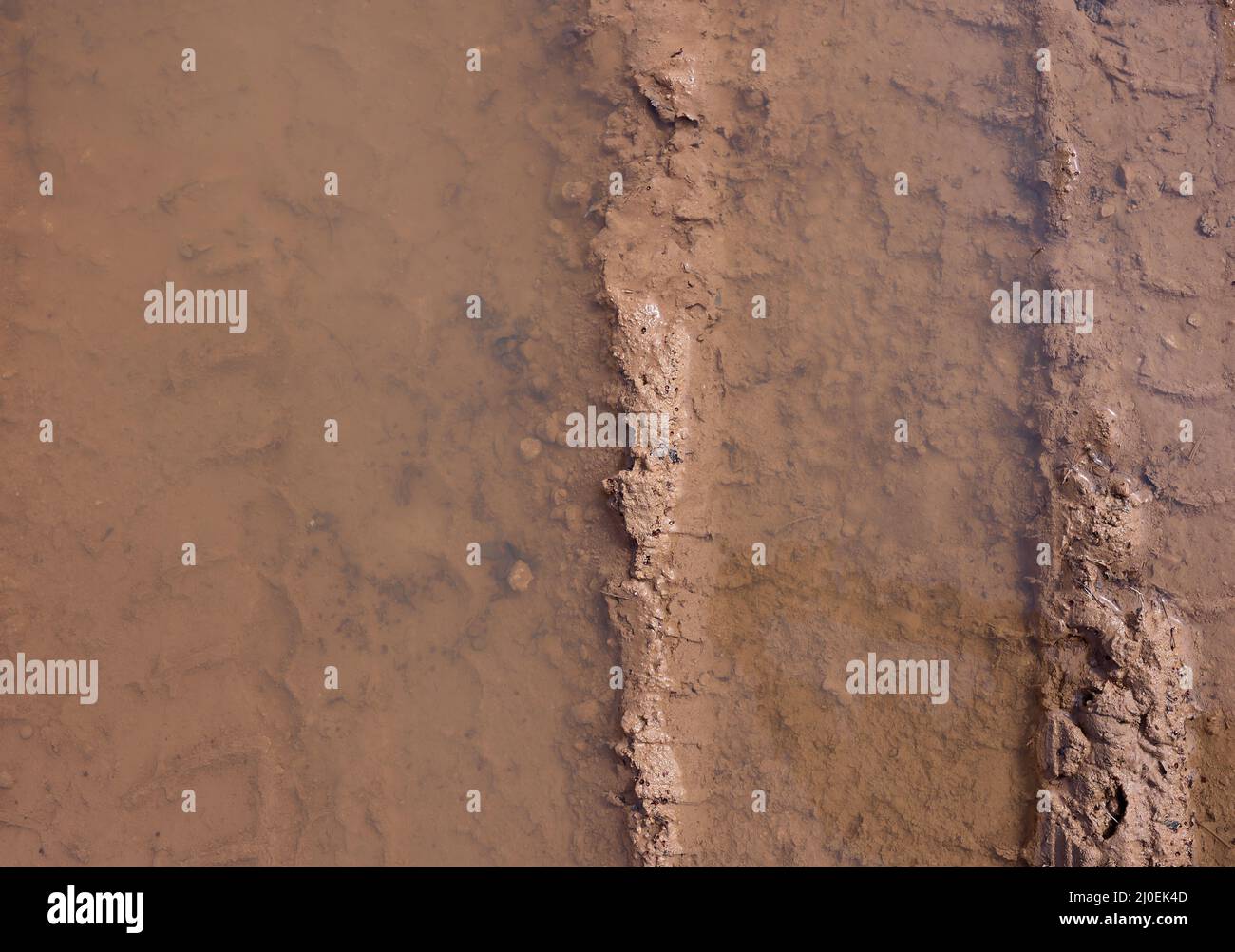 detail of tractor or heavy machinery wheel track over muddy puddle of ...