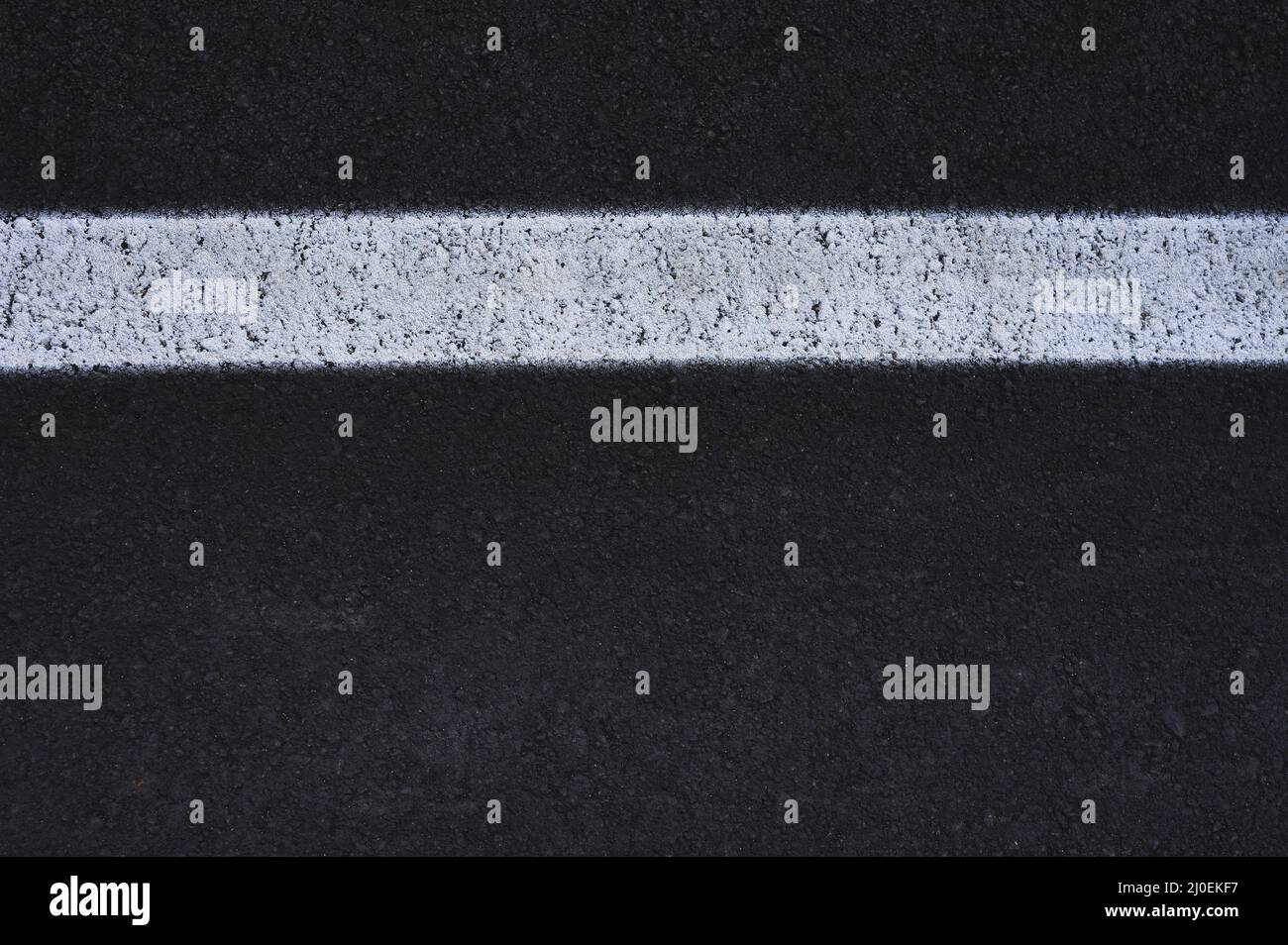 detail of a white line painted on the side of an asphalt road under ...