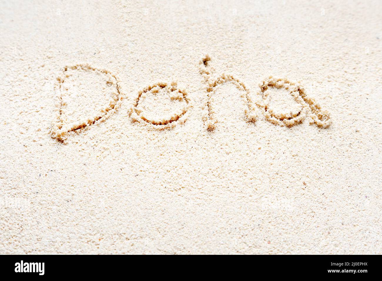Handwriting words "Doha" on sand of beach Stock Photo - Alamy