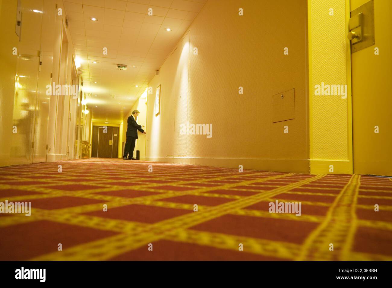 Low angle looking down a hotel corridor, of a businessman checking into ...