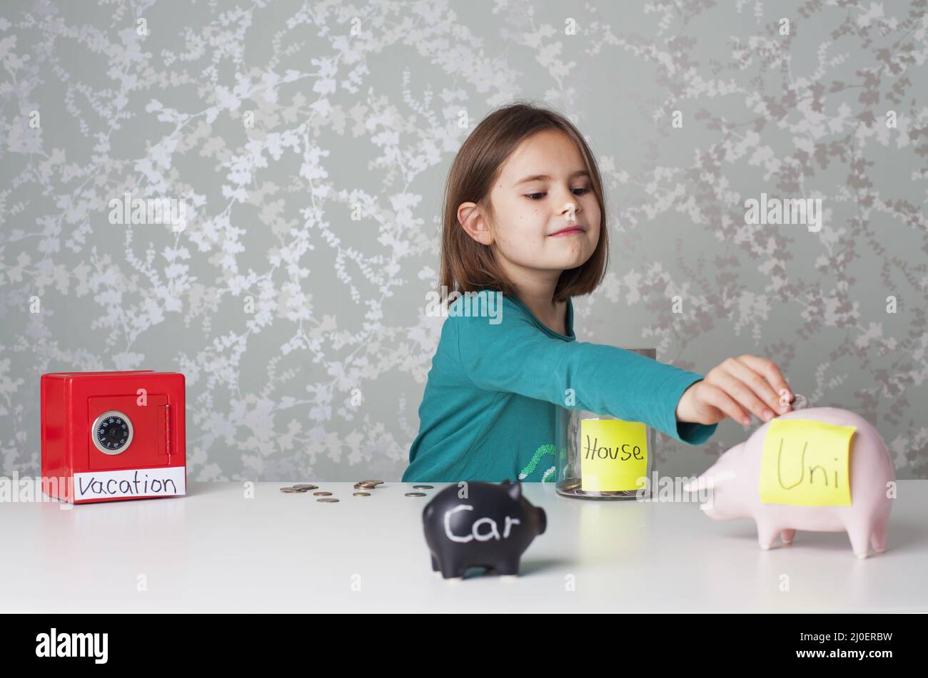 Girl holding a coin surround by piggy banks and money boxes Stock Photo ...