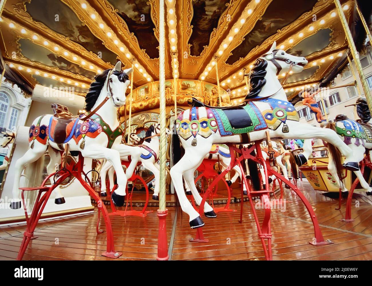 White painted horses in a carousel decorated with lights and gold Stock ...