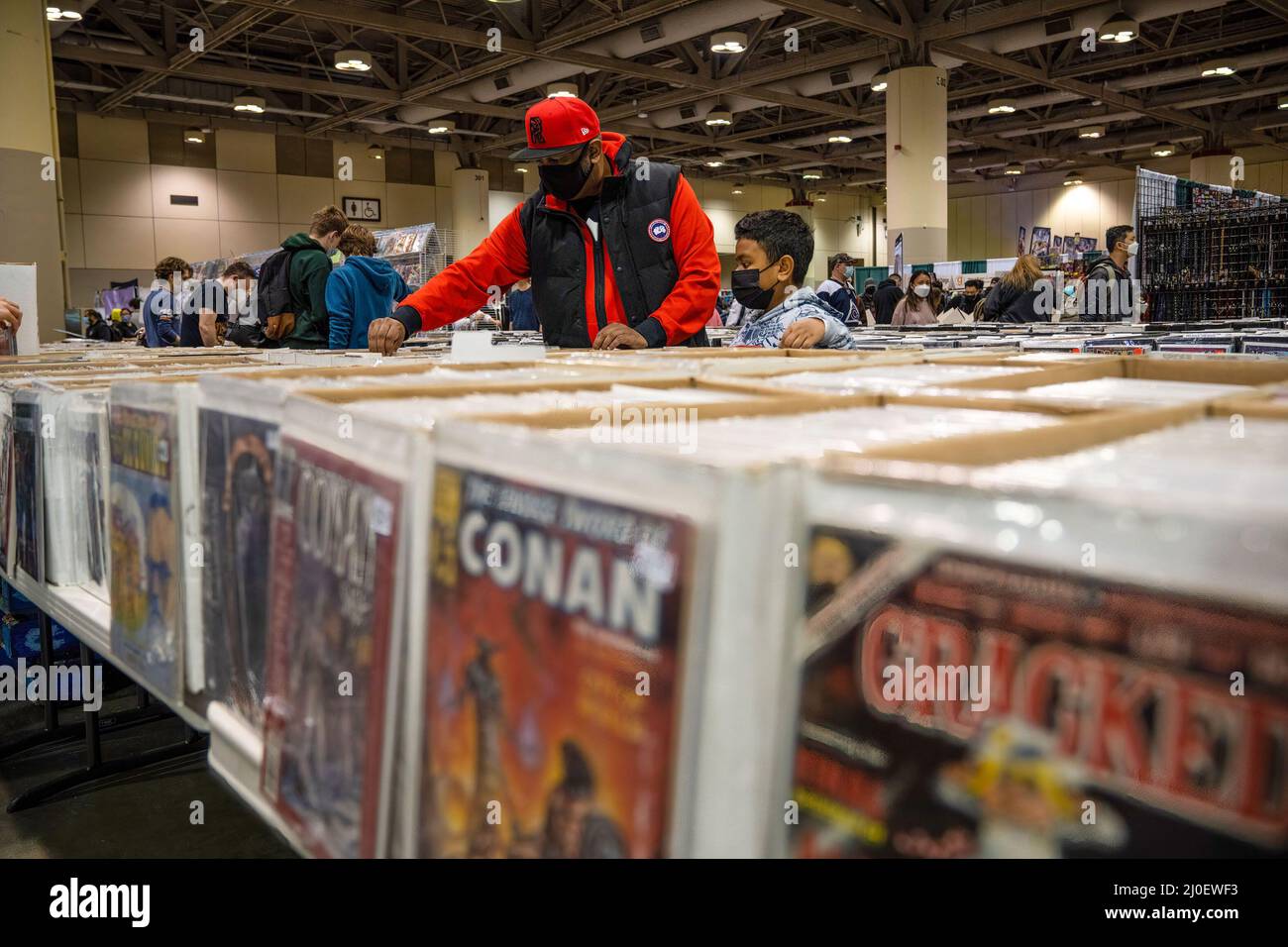 A father and son browse for comic books during the event. People gather ...