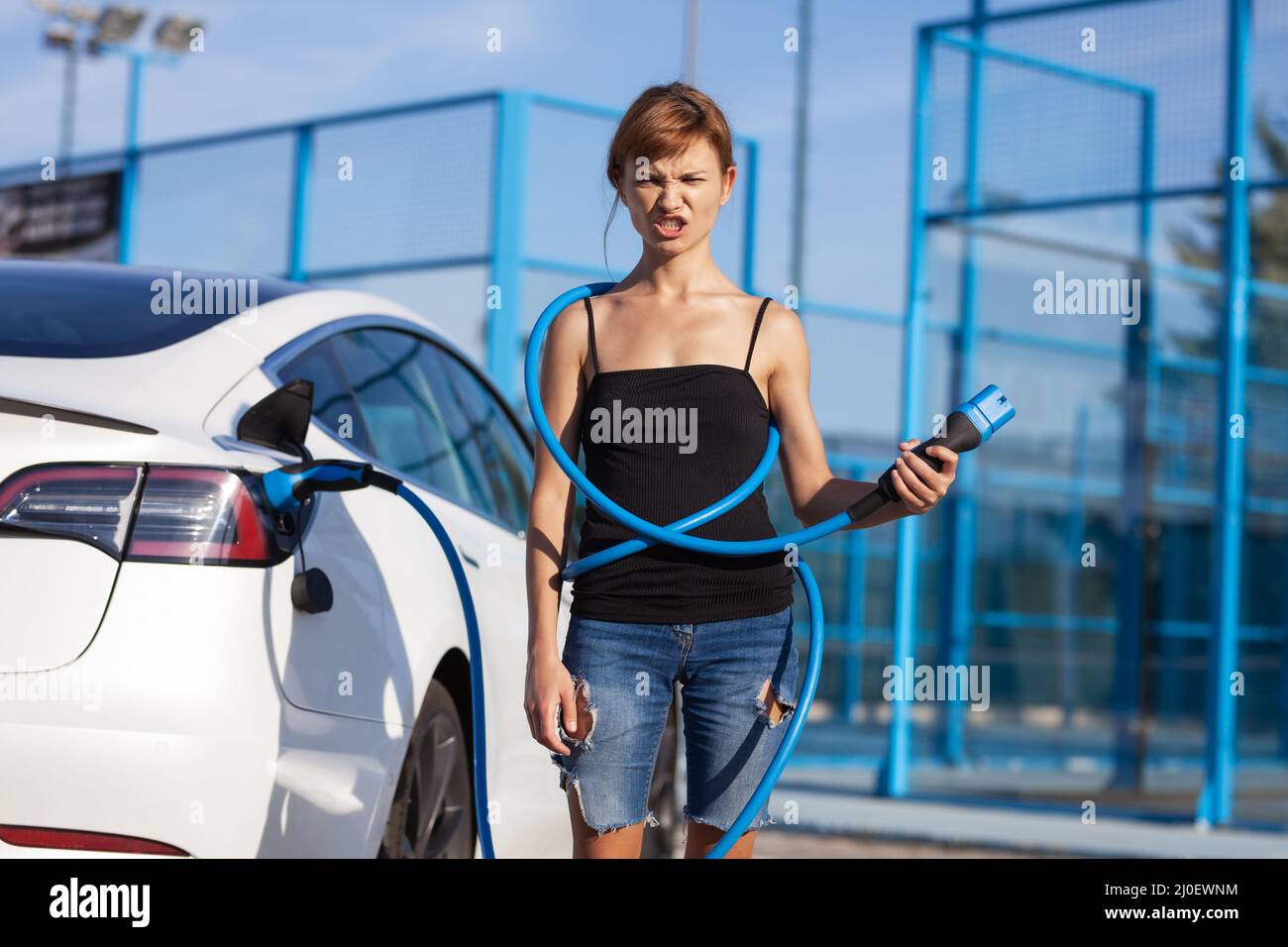 Beautiful young girl next to an electric car. Clumsy wrapped and ...