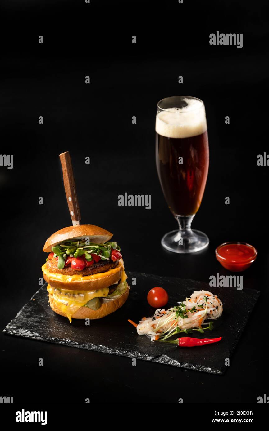 Big delicious burger on the board with a glass of beer Stock Photo - Alamy
