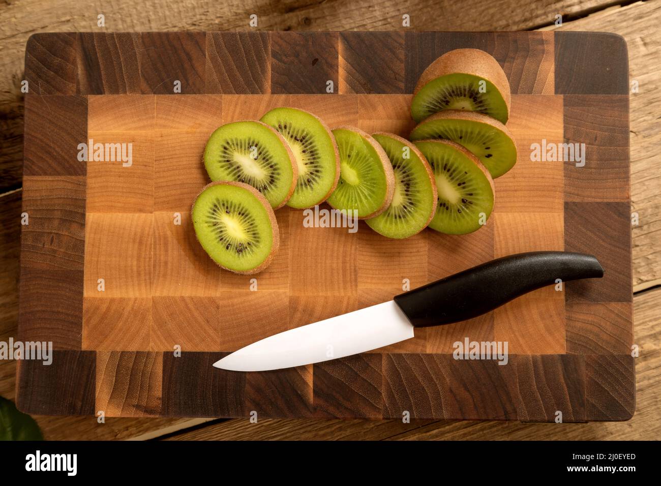 Green kiwi sliced on wooden carving board Stock Photo - Alamy