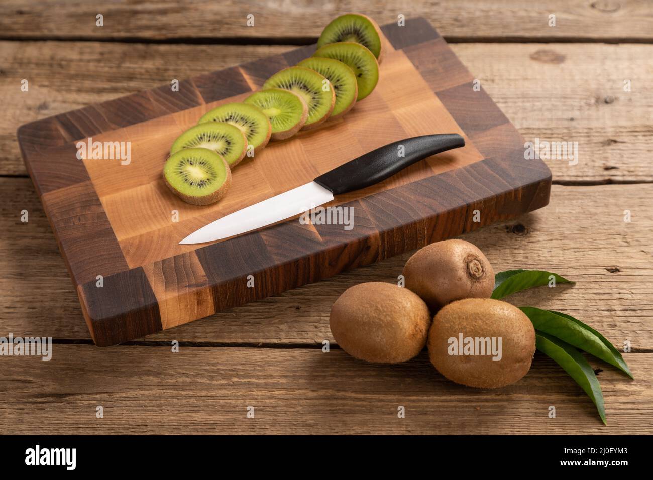Green kiwi sliced on wooden carving board Stock Photo - Alamy