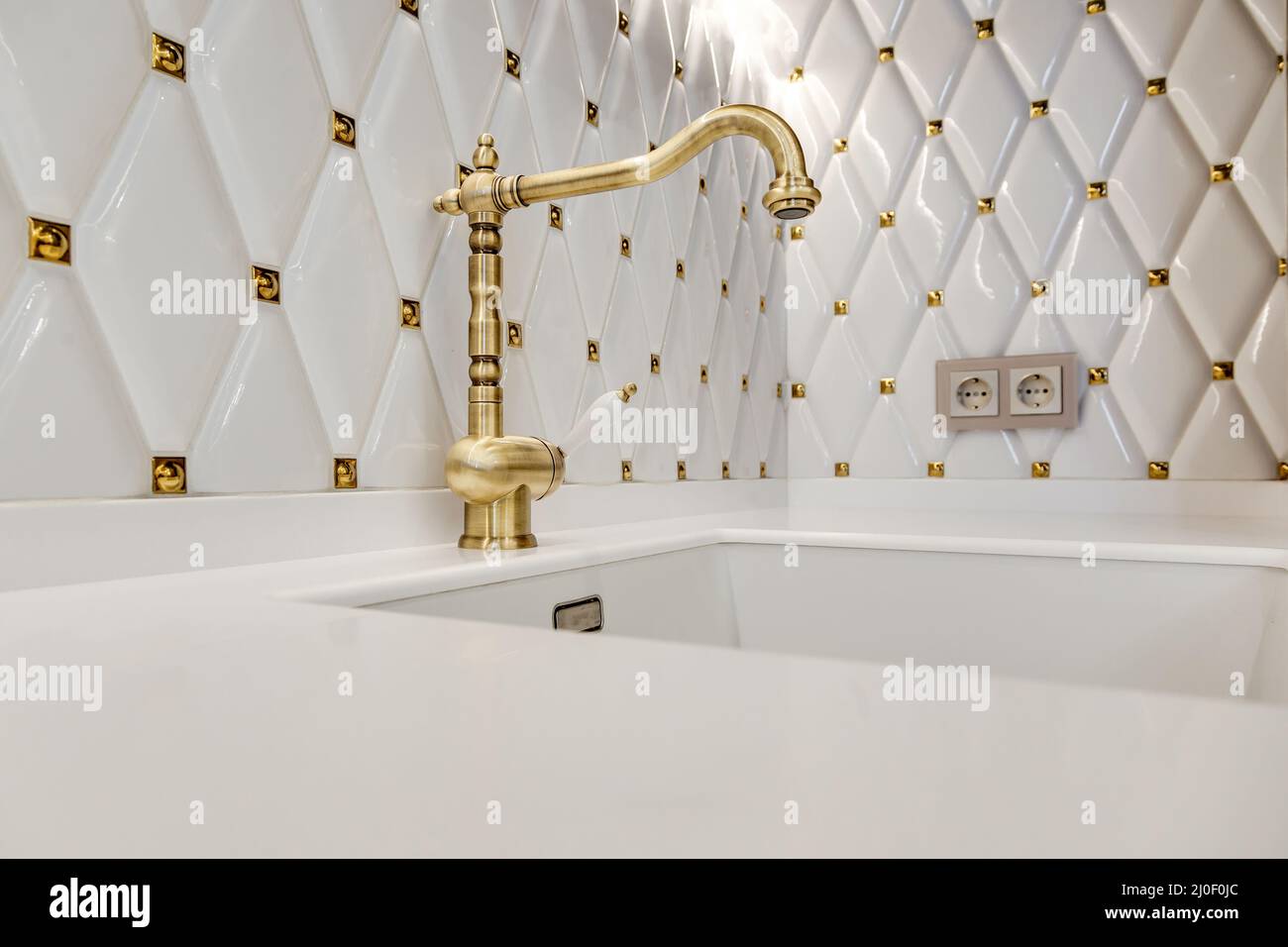 Sink with faucet made of bronze on a white glossy kitchen worktop Stock ...