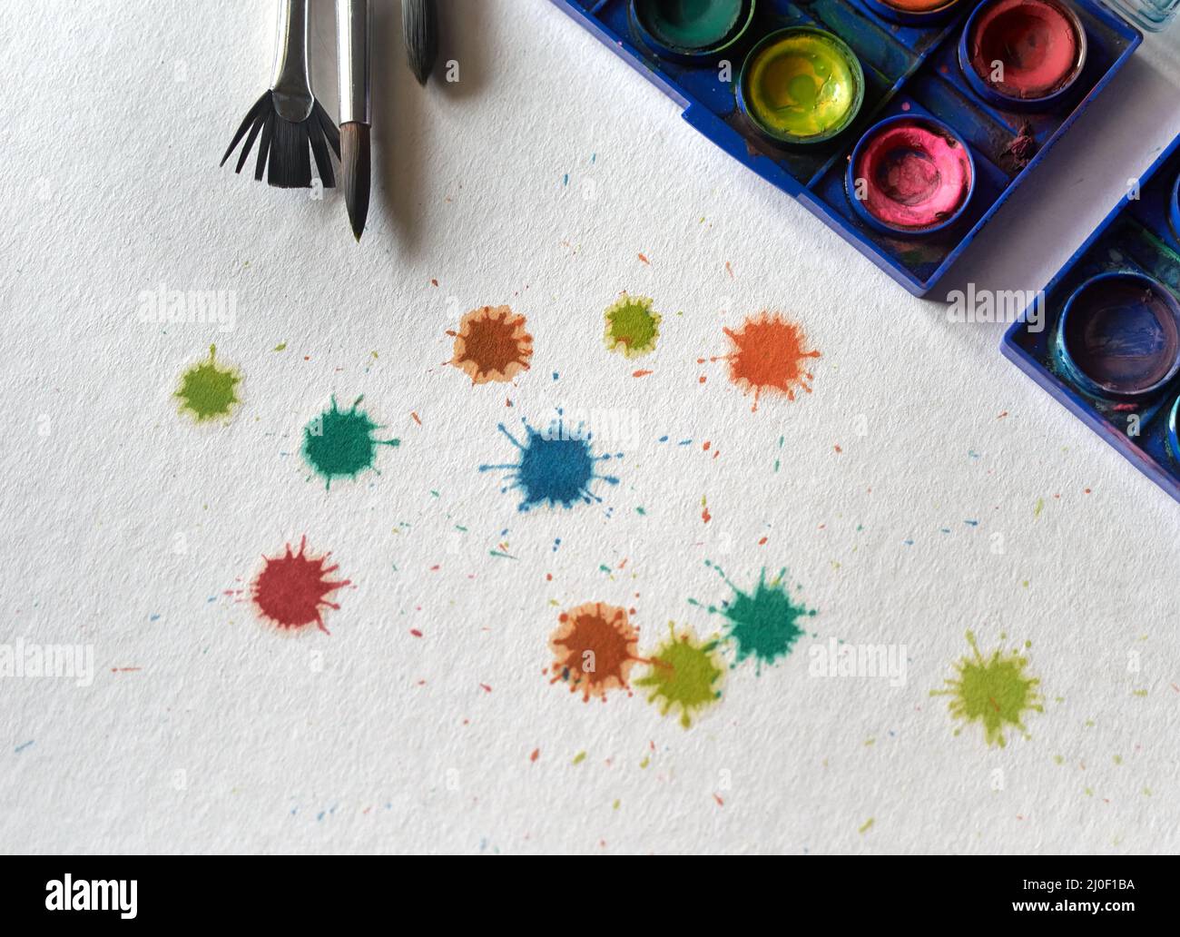 Paintbrushes with the color palettes and the color stains on the rough ...