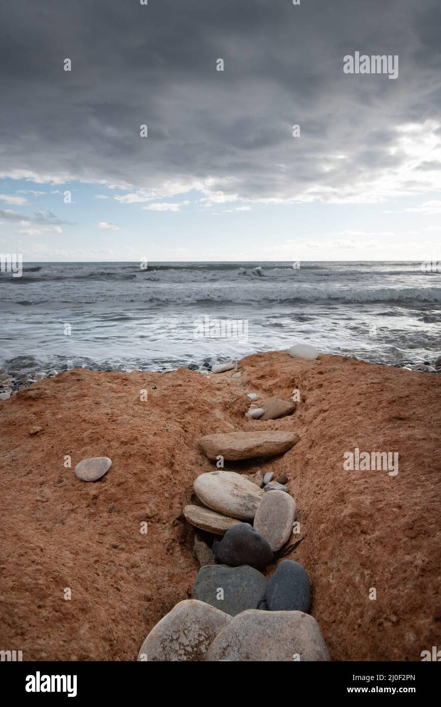 Pebbles on a red wavy beach and stormy cloudy sky. Larnaca Cyprus Stock ...