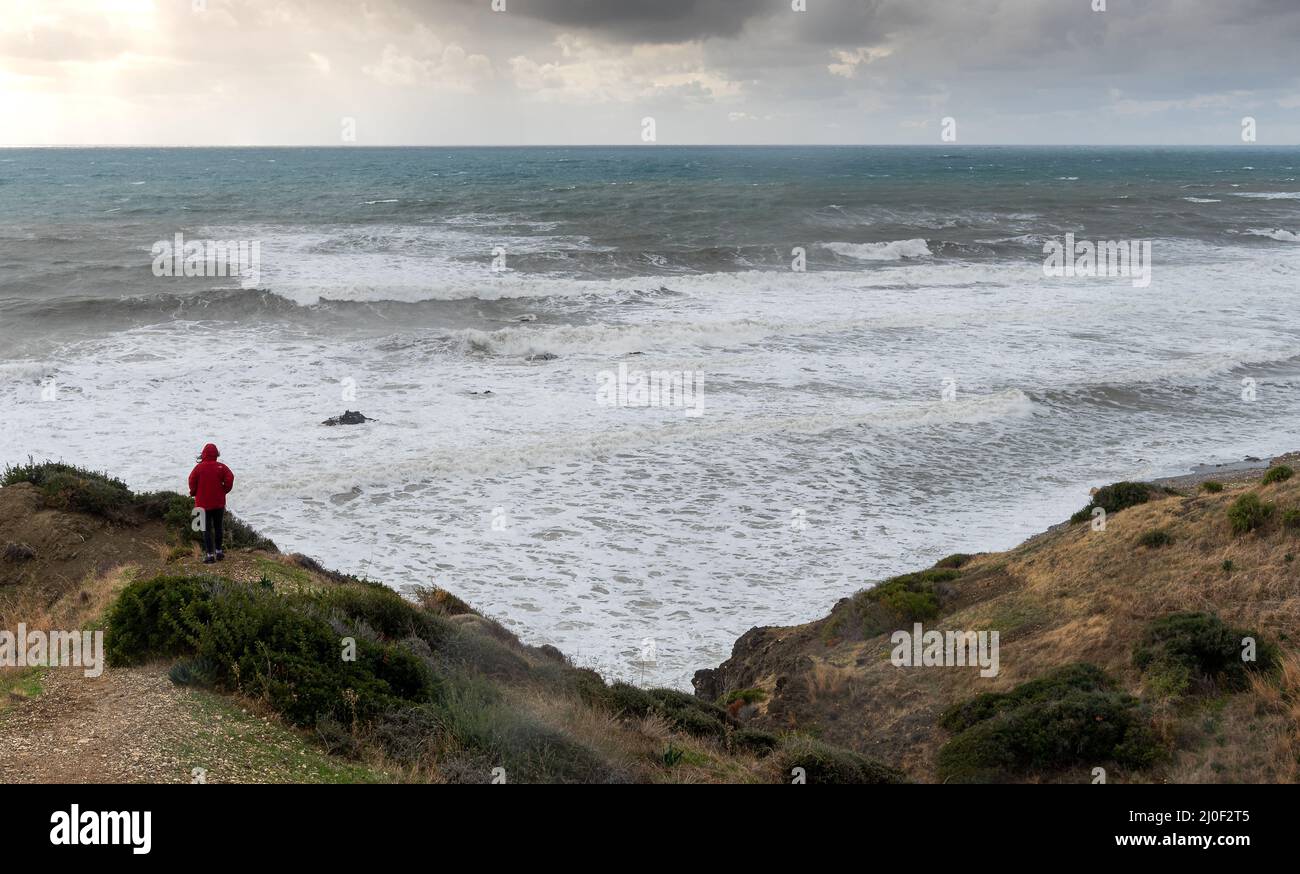 Unrecognised person standing the edge of a cliff. dramatic stormy sea ...