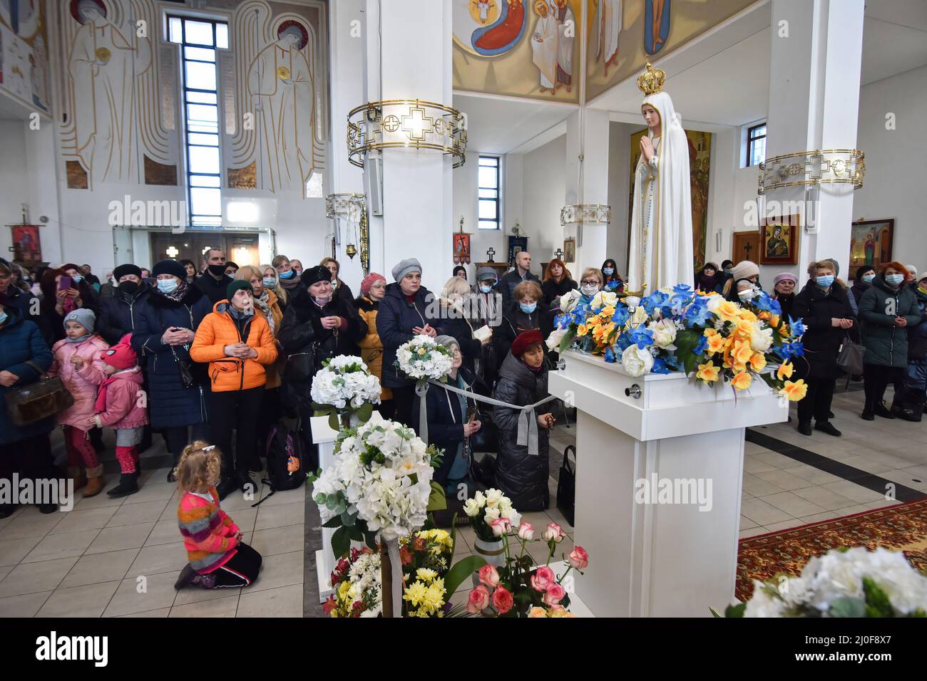Lviv, Ukraine. 18th Mar, 2022. A kid kneels before the statue as people ...