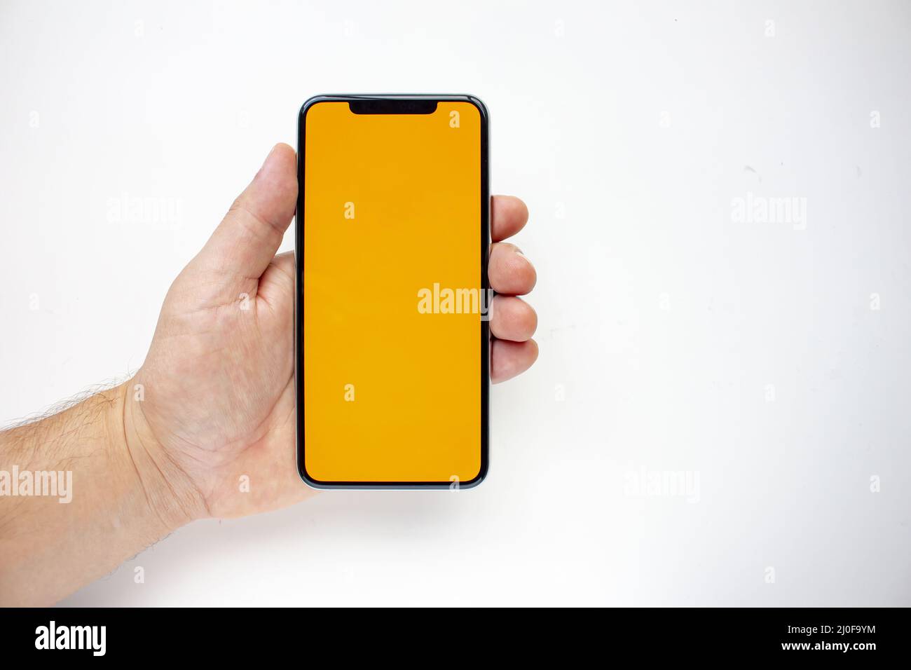 A person holding an Smart Phone with a orange screen on a white ...