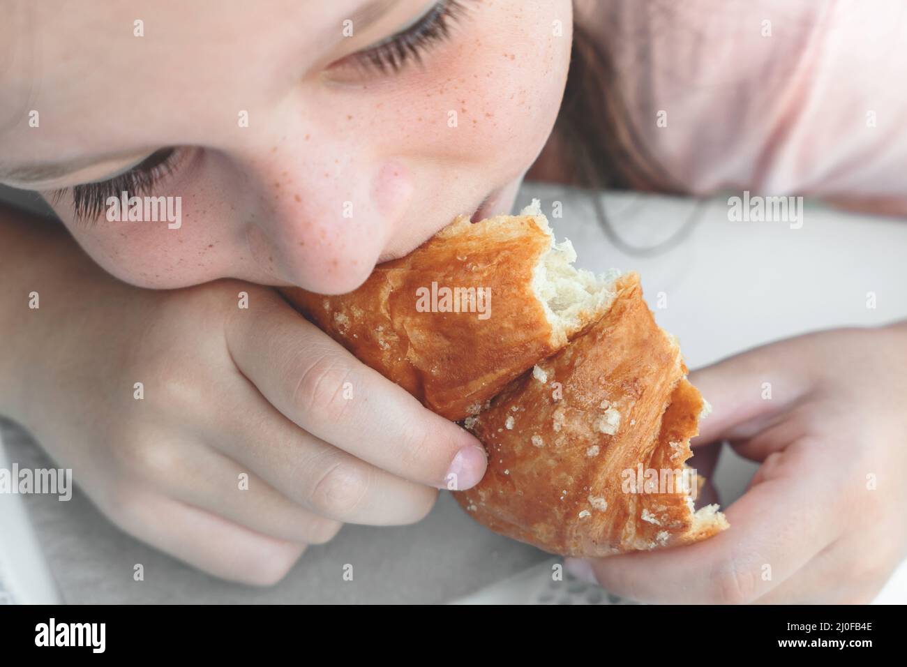Young girl eat croissant Stock Photo - Alamy